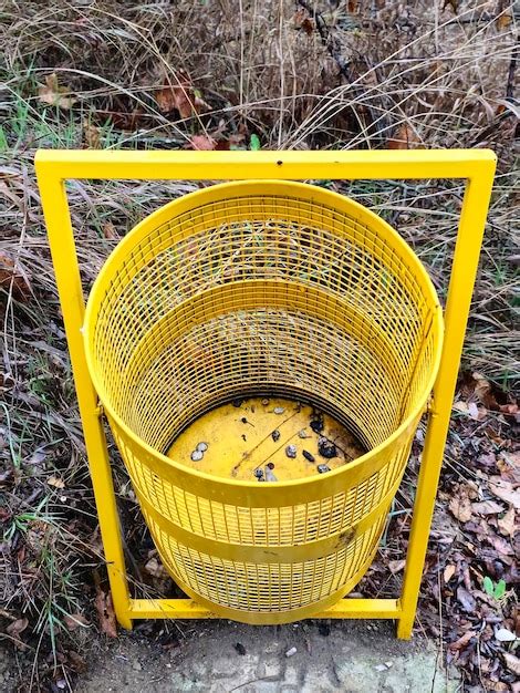 Premium Photo A Yellow Metal Trash Can In The Grass
