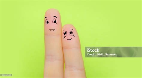 한 남자와 여자의 얼굴이 그려진 두 손가락이 햇살 가득한 하늘 배경의 눈부심에 미소짓고 기뻐하고 있습니다 사람이 없는 사랑과 관계의 개념 개념에 대한 스톡 사진 및 기타