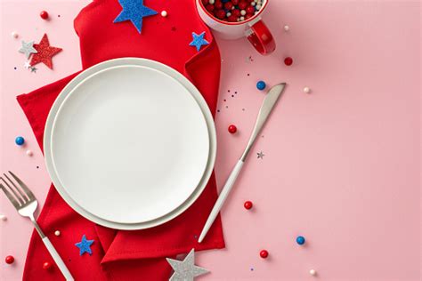 7 월 4 일 축하 장면 접시 포크 나이프 컵 냅킨 별 스팽글 둥근 스프링클이있는 테이블 배열의 평면도 텍스트를 위한 빈 공간이 있는 파스텔 핑크 배경 0명에 대한 스톡