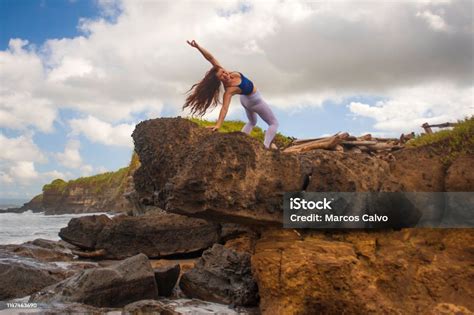 젊고 매력적이 고 집중 된 여 자가 건강 한 자연 라이프 스타일에서 아름 다운 해변 바위 절벽에서 Acroyoga 균형 운동과 요가 유연성과 명상 연습 건강한 생활방식에
