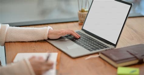 편안한 흰색 스웨터를 입은 여성이 노트북 컴퓨터에서 작업하는 동안 일기에 창의적인 아이디어를 쓰고 있는 자른 이미지 노트북 빈