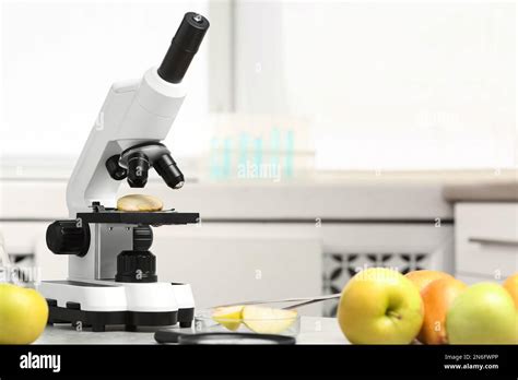 Microscope With Slice Of Apple On Table In Laboratory Space For Text