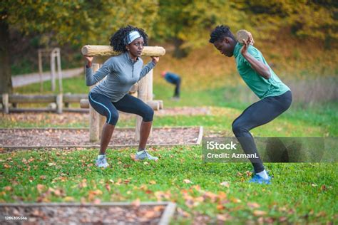 Athletes Doing Back Squat With Logs In Outdoor Exercise Area Stock