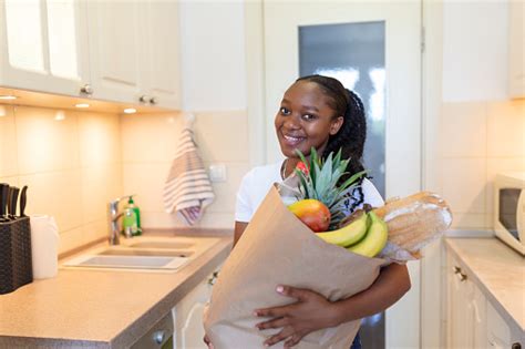 과일과 채소로 가득 찬 종이 쇼핑백을 들고 있는 건강한 긍정적 행복한 여성 부엌에 서있는 채소와 식료품 쇼핑 백을 들고 젊은 여자 요리하기 음식 준비에 대한 스톡 사진 및