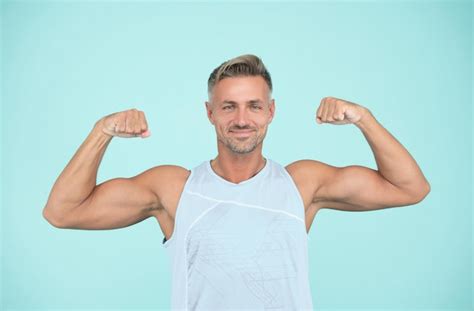 행복한 근육질의 남자 파란색 배경 스포츠맨 근육질 팔 팔뚝 삼두근 근육질 남자를 보여주는 프리미엄 사진