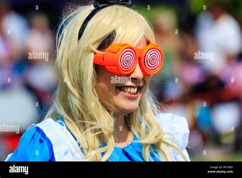 Head shot of young Japanese woman, with spiral glasses, dressed as 'Alice in Wonderland' smiling ...