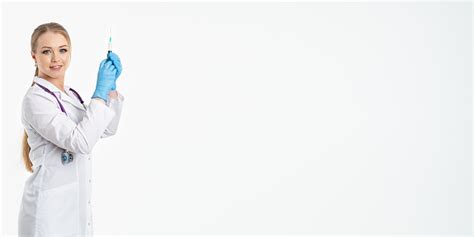 마스크와 흰색 코트를 입은 젊은 간호사가 주사 독감 주사 공대용 바늘이 달린 주사기를 들고 있습니다 전염병에서 인플루엔자에 대한 예방 접종 및 보호의 개념 복사 공간을