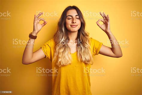 노란색 고립 된 배경 위에 티셔츠를 입고 젊은 아름다운 여성은 손가락으로 명상 제스처를하고 눈을 감고 미소 요가 개념입니다 한 명의 여자만에 대한 스톡 사진 및 기타 이미지