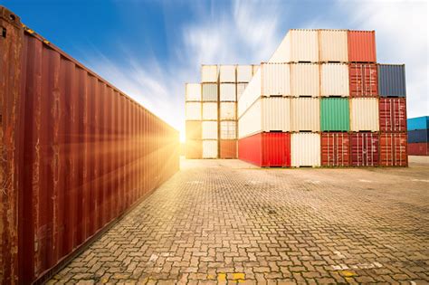 지게차 리프팅 화물 컨테이너 선박 야드에서 또는 도킹 화물 컨테이너 스택 교통 가져오기 내보내기 및 물류 산업 개념에 대 한 배경으로 일출 하늘에 대 한 야드 건설 프레임에