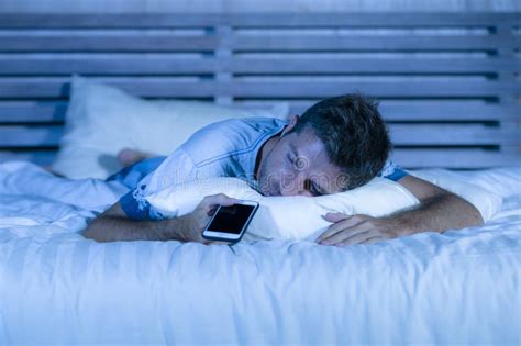 Attractive Tired Man In Bed Falling Asleep While Using Mobile Phone