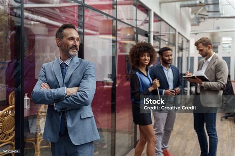사무실에 서서 동료들의 배경에 옆을 바라 보는 잘 생긴 사업가 미소 짓기 20 24세에 대한 스톡 사진 및 기타 이미지 20