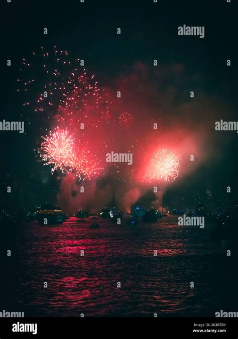 A Vertical Shot Of Exploding Bright Red July 4th Fireworks Over Water