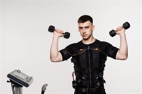 Ems 슈트를 입은 근육질의 남성 운동선수는 흰색 배경에 근육을 자극하기 위해 전기 충격을 사용합니다 전기 근육 자극 슈트에서 스포츠 훈련 20 24세에 대한 스톡 사진 및