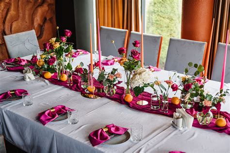 분홍색과 주황색 꽃 장미와 양초 과일로 장식 아름답게 조직 된 이벤트 홀에서 손님을 위해 준비된 테이블 연회 생일 파티나 결혼식 피로연을 위한 테이블 세트 0명에 대한 스톡