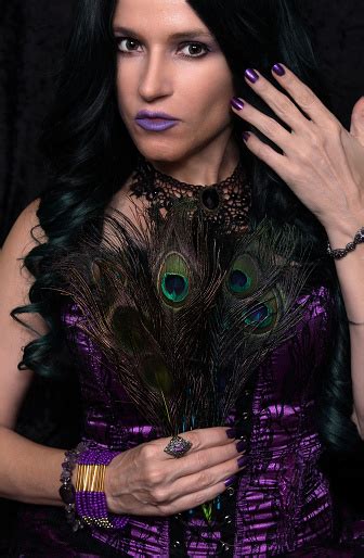 녹색과 검은색 머리와 공작 깃털을 가진 보라색 코르셋을 입은 여자가 카메라를 향해 포즈를 취하고 있다 갈색 머리에 대한 스톡 사진 및 기타 이미지 Istock
