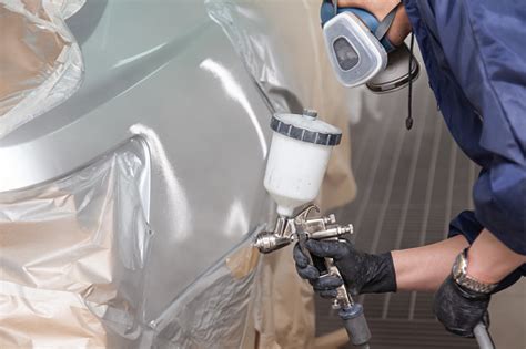 한 남성 근로자가 사고로 손상된 후 차체의 일부를 스프레이 건으로 칠합니다 작업장에서 수리하는 동안 차량에서 후방 펜더 자동차 서비스 산업 전문 직종사 가리기에 대한 스톡