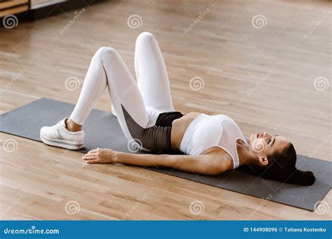 Slim Dark Haired Girl Dressed In White Sports Clothes Has A Work Out On