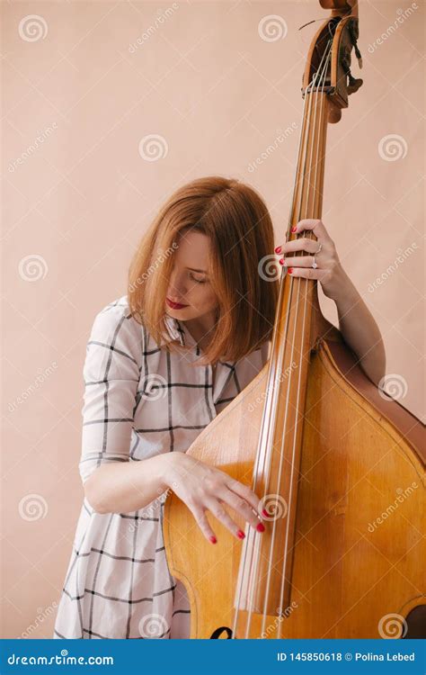 Beautiful Young Woman Musician Sitting On A Vintage Double Bass On A