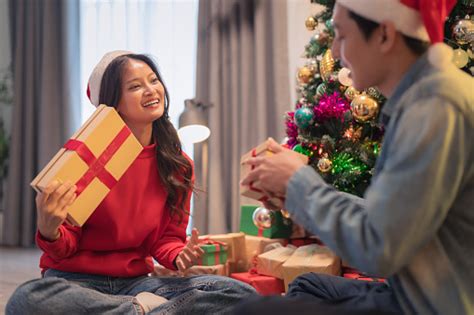 빨간 스웨터를 들고 기쁨에 가득 찬 여자 남자와 크리스마스를 축하 남자 축제 분위기에는 장식 된 트리와 화려한 선물이 포함되어 따뜻한 휴가 정신을 만듭니다 12월에 대한