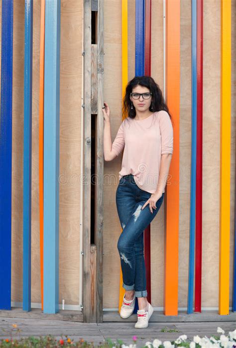 Красивая высокорослая девушка с длинным брюнет волос в стеклах стоя около красочной предпосылки