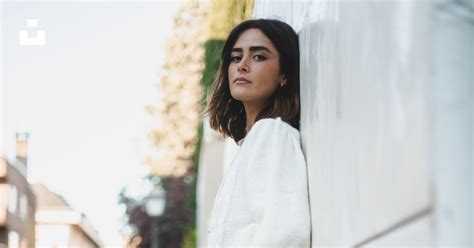 흰색 긴 소매 셔츠와 흰색 바지에 검은 Dslr 카메라를 들고 있는 여자 사진 Unsplash의 무료 모다 이미지