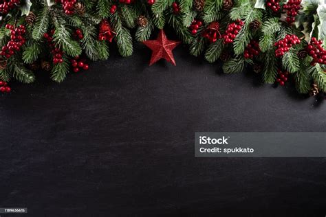 크리스마스 배경 개념입니다 검은 나무 배경에 가문비 나무 가지 소나무 콘 빨간 열매와 종 크리스마스 선물 상자 빨간 공의 상단