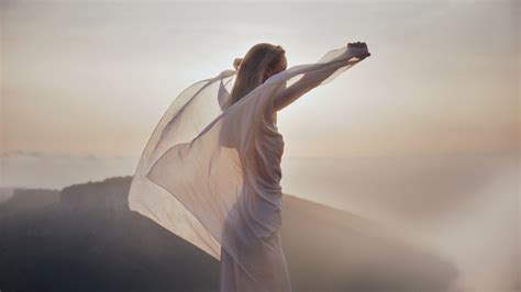 긴 금발 머리를 가진 아름다운 신비한 여자가 구름 속에서 일몰에 천으로 관능적인 춤을 추고 있다 바람에 대한 스톡 사진 및 기타