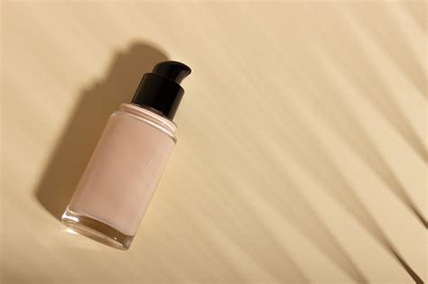 그림자가 있는 배경에 유리 병에 파운데이션 복사 공간이 있는 베이지 색 배경의 얼굴 보정기입니다 복사 공간을 갖춘 패키징 모형 개선에 대한 스톡 사진 및 기타 이미지