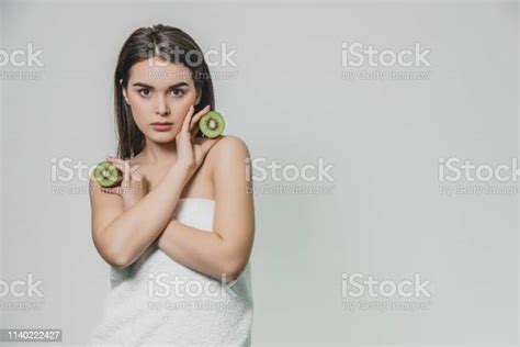 흰색 바탕에 서 있는 젊은 예쁜 여자 이 시간 동안 그는 그의 손을 교차 하 고 가슴의 수준에서 키 위를 보유 하 고 있습니다 가까운에 대한 스톡 사진 및 기타 이미지