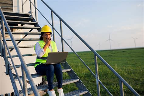 제복을 입고 노트북을 사용하여 풍력 터빈 농장에서 전기 에너지를 생산하기 위해 교대로 문서 검사 작업을 수행하는 여성 엔지니어 녹색 생태 전력 에너지 발전 풍력 지속 가능한