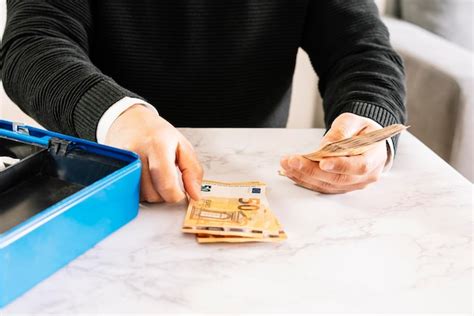 Premium Photo Man Counting Banknotes Next To A Metal Security Box On A Table Premium Photo Man Counting Banknotes Next To A Metal Security Box On A Table