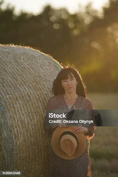 Seorang Wanita Berdiri Di Atas Tumpukan Jerami Dan Memegang Topi Jerami Di Tangannya Foto Stok