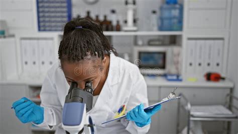 African American Woman Scientist Examining Samples Under A Microscope In A Laboratory Setting