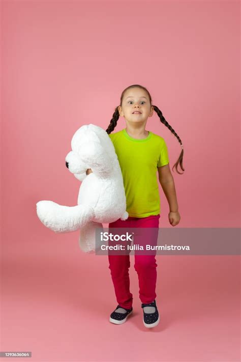 밝은 녹색 티셔츠와 빨간 바지에 피그 테일과 전체 길이 기뻐하는 아이는 분홍색 배경에 고립 된 흰색 테디 베어와 함께 실행 2월에 대한 스톡 사진 및 기타 이미지 Istock