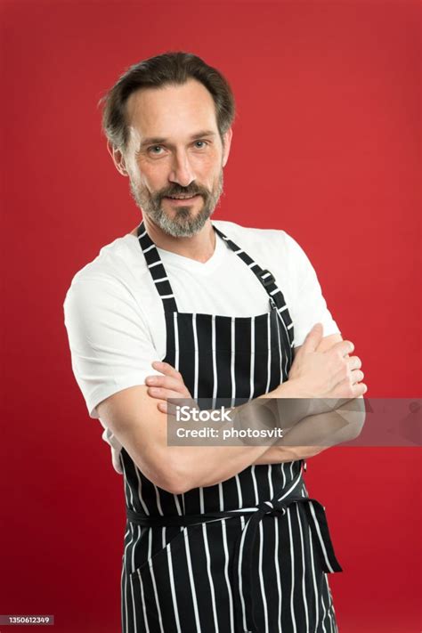 에이프런 레드 배경에 자신감 성숙한 잘 생긴 남자 그는 베이커 정원사 요리사 또는 청소기 수 있습니다 모든 것에 좋습니다 멀티 태스킹과 전문 직업 더러운 작업에 대 한