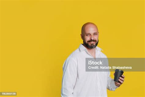 흰색 셔츠를 입은 잘생긴 진지한 중년 남성이 미소를 지으며 복사 공간이 있는 노란색 배경에 커피 한 잔을 들고 있다 노인의 초상화 40 49세에 대한 스톡 사진 및 기타