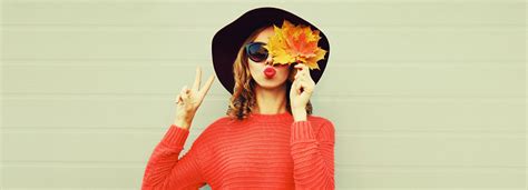 모자를 쓰고 입술을 불고있는 노란 단풍 나무 잎으로 눈을 가리는 아름다운 젊은 여성의 가을 초상화 회색 배경에 니트 스웨터 25 29세에 대한 스톡 사진 및 기타 이미지