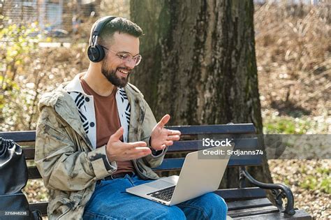 젊은 Dj는 공원에 앉아서 자신이 만든 새로운 노래와 비트를 듣고 무선 헤드폰으로 노트북 컴퓨터에서 재생합니다 음악을 만드는 사람 새로운 창작물을 위해 듣는 것을 행복하게