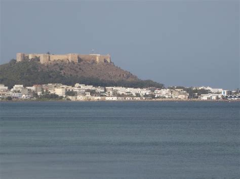 A Large Body Of Water Next To A City On Top Of A Hill In The Distance