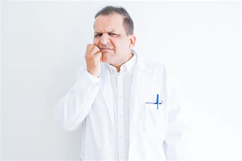 중간 나이 의사 남자는 흰색 배경 위에 의료 코트를 입고 스트레스와 입 물고 손톱에 손으로 긴장 찾고 불안 문제 감정에 대한 스톡 사진 및 기타 이미지 Istock