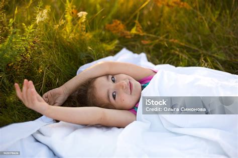 소녀는 풀밭에서 침대에서 자고 달콤한 스트레칭과 하품은 졸리고 신선한 공기에서 좋은 아침을 보낸다 친환경적이고 건강한 수면 모기로부터의 보호 깨끗한 자연 생태학 어린이 건강