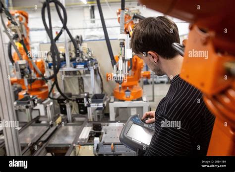 Young Man Programming Industrial Automatic Robot In Automotive Industry