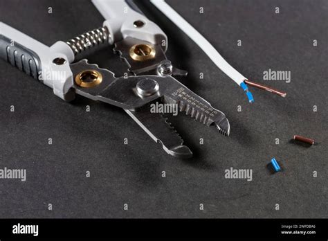 Removing The Insulation From The Conductor Using A Tool Wire Stripping Tool On Dark Background