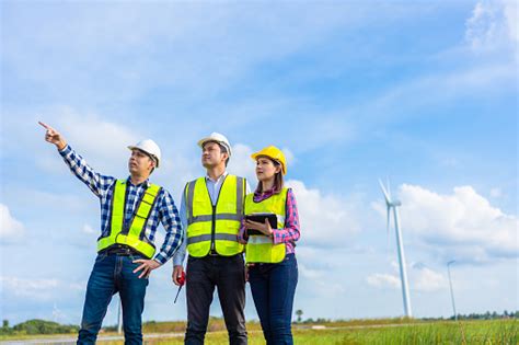 재생 에너지 산업의 기술 지표 및 사업 계획을 검토하는 엔지니어링 전문가들이 현장 평가 중에 풍력 터빈 앞에서 태블릿을 사용하고 있습니다 25 29세에 대한 스톡 사진 및