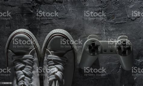 회색 콘크리트 배경에 오래 된 운동화와 복고풍 게임 패드 맨 위 보기 Brand Name Video Game에 대한 스톡 사진