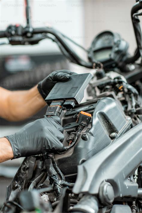 작업장에서 수리하는 동안 오토바이의 배선을 연결하는 보호 장갑을 낀 전기 기사 또는 수리공 클로즈업 사진 Unsplash의 오토바이 이미지