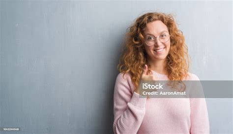 회색 그런 지 이상 젊은 빨강 머리 여자 확인 서명 손가락 우수한 기호를 엄지손가락을 하 고 큰 미소로 행복 안경을 착용 벽