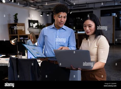 Asian Male And Female Colleagues Discussing Over Laptop While Working