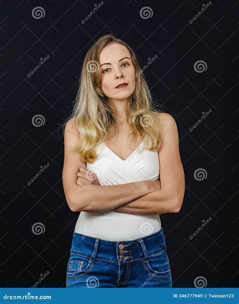Adult Woman In White T Shirt And Blue Jeans Looks At You Seriously
