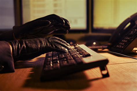 Man Attacker Hacker In Black Gloves On His Hands Working On A Computer Keyboard At An Office